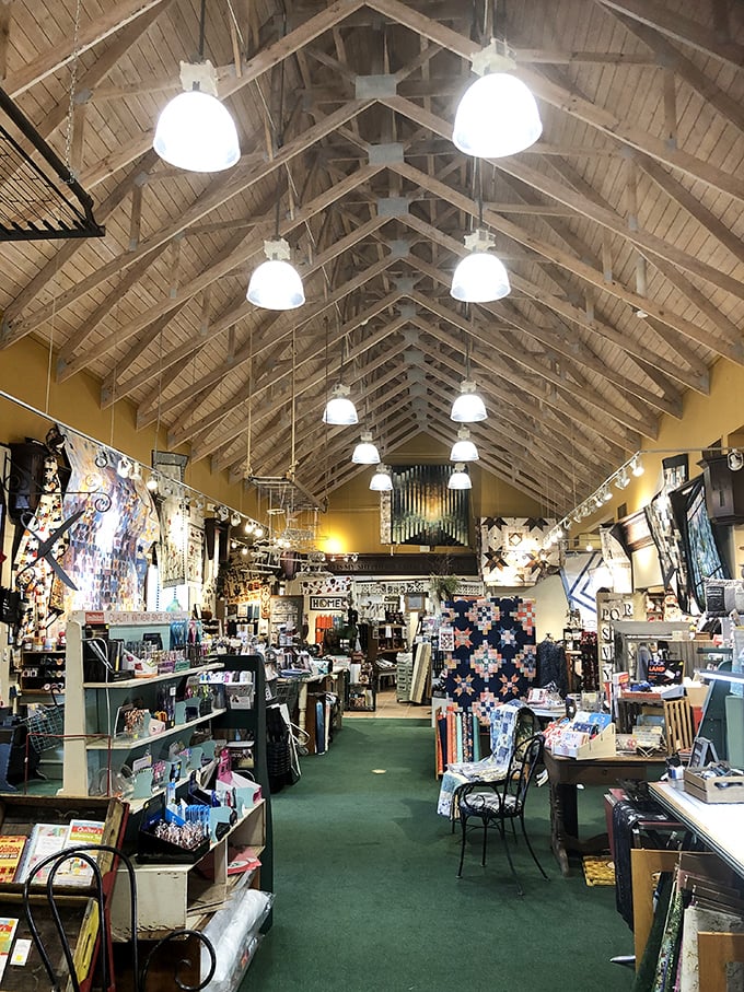 Soaring cathedral ceilings and exposed wooden beams create a sanctuary-like atmosphere where quilting dreams take flight among thousands of fabric possibilities.