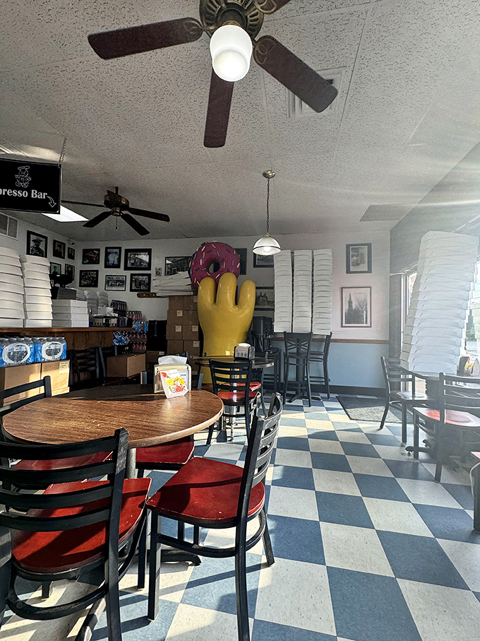 Inside, the iconic yellow hand statue stands guard over the checkered floor, a silent sentinel protecting the sacred art of donut-making.