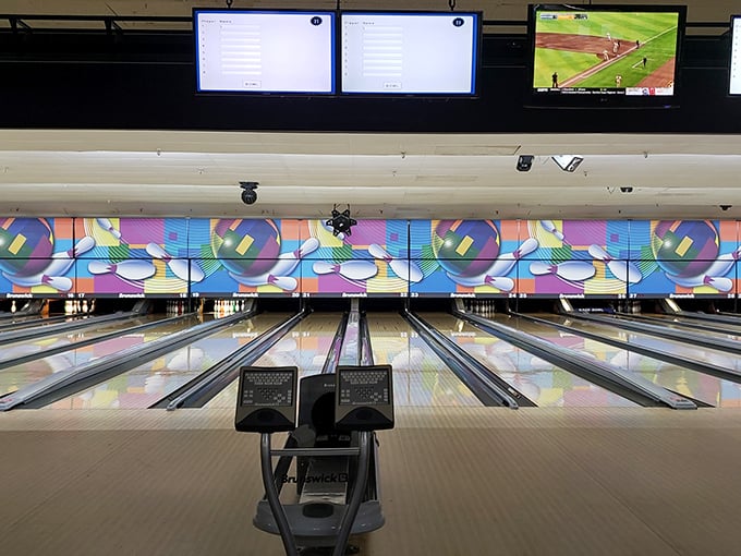 Polished lanes stretch toward colorful backdrops, where digital screens keep score while a baseball game plays nearby&mdash;multitasking at its finest.