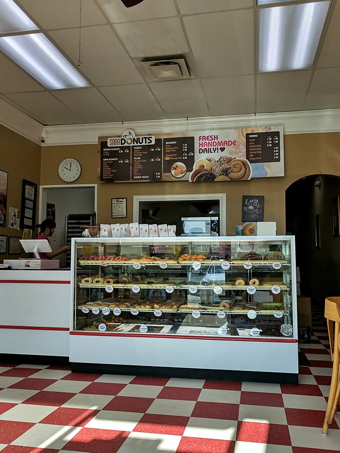 The classic red and white checkered floor sets the stage for donut drama, where glass cases showcase the day's stars waiting for their curtain call.