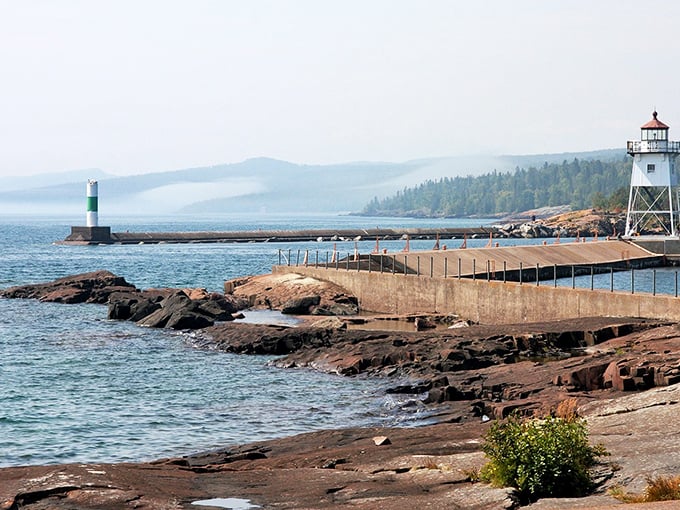 The iconic lighthouse stands sentinel over Lake Superior's waters, where the harbor's protective embrace has sheltered boats for generations.