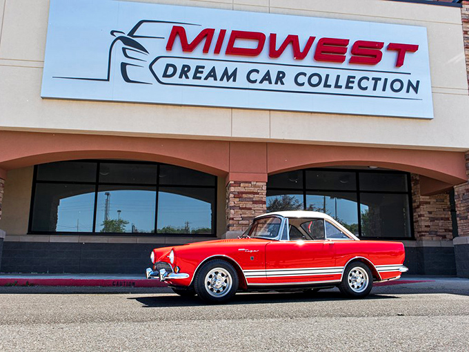 This sleek red Sunbeam Tiger sits proudly outside, teasing passersby with a glimpse of the four-wheeled wonders awaiting within. Photo credit: Midwest Dream Car Collection
