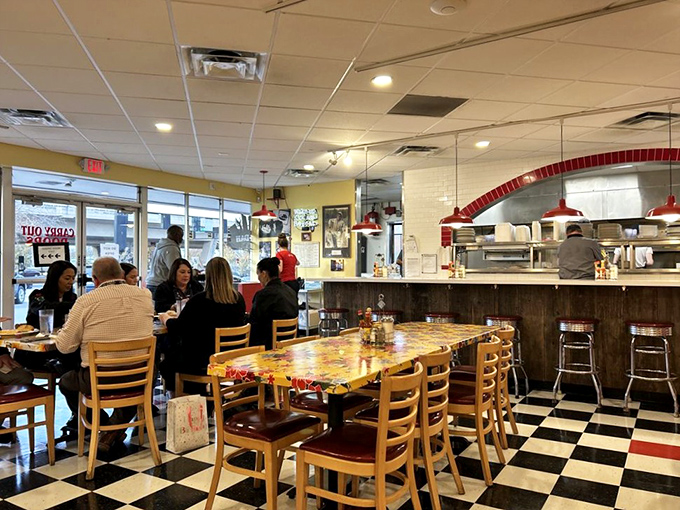 Inside, the classic checkered floor meets colorful community tables where strangers become friends over shared maple syrup and coffee refills.