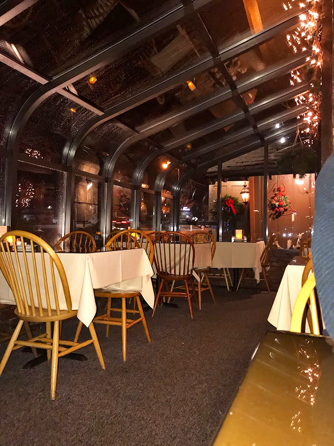 The glass-enclosed porch creates that magical dining space where evening twilight and twinkling lights conspire to make every meal feel special.