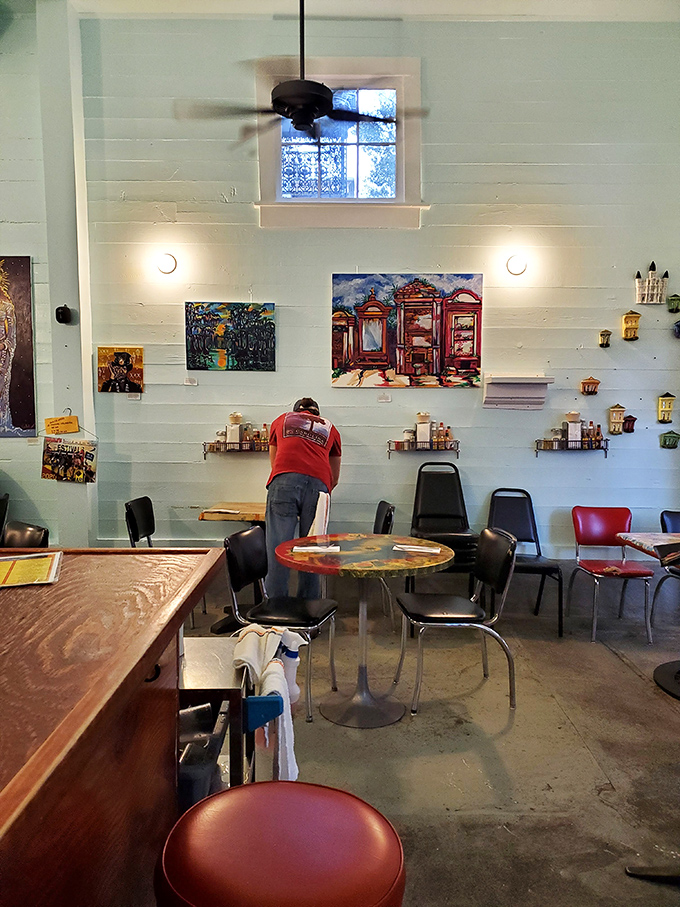 Local art adorns the light blue walls, creating a gallery-like atmosphere where both the paintings and plates compete for your attention.