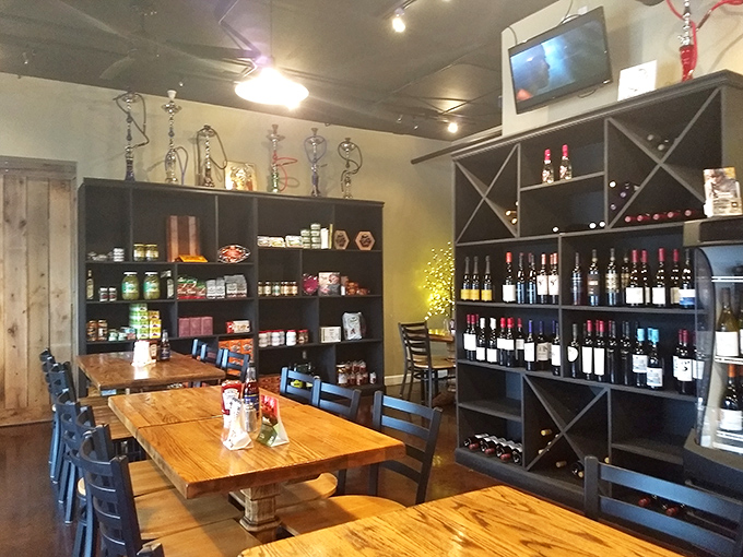 Inside, rustic wooden tables meet Mediterranean market vibes. Wine bottles stand at attention like soldiers guarding flavor, ready to complement your meal with perfect pairings.