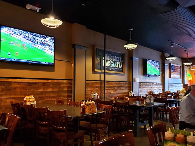 The dining area strikes that perfect balance: rustic wooden tables, warm lighting, and TVs for catching the game while you surrender to your barbecue fantasies.