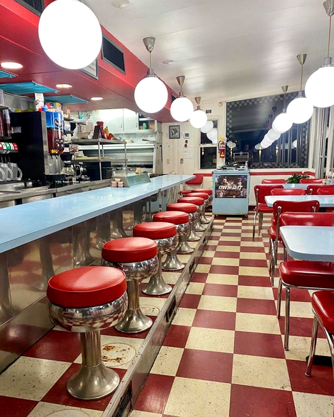Step into a time capsule where red vinyl stools and checkerboard floors promise that whatever comes on your plate will be worth the wait.