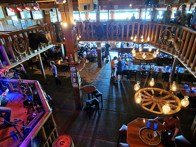 Step into a time machine disguised as a dining room, where wagon wheel chandeliers illuminate two levels of cowboy-themed splendor that John Wayne would approve of.