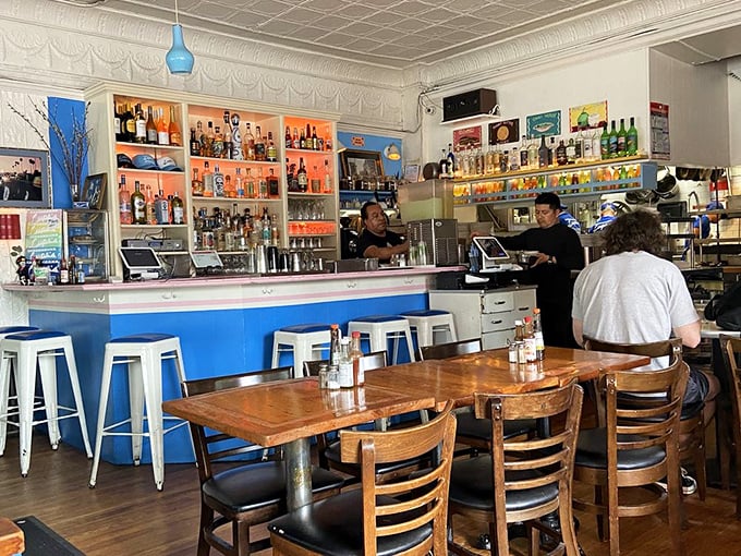 The interior bar area balances nostalgia and function with its vintage tin ceiling, vibrant blue counter, and well-stocked shelves &ndash; a testament to decades of serving thirsty New Yorkers.