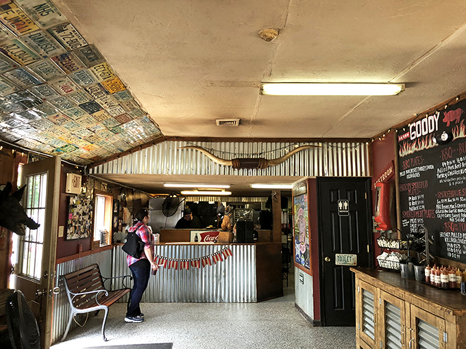 License plates from across America tile the ceiling, silent testimonials from barbecue pilgrims who found salvation in this unassuming temple of smoke.