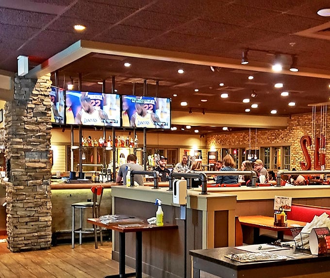 Where smoke meets socializing—the warm wood tones, stone columns, and strategically placed TVs create the perfect backdrop for serious meat appreciation.