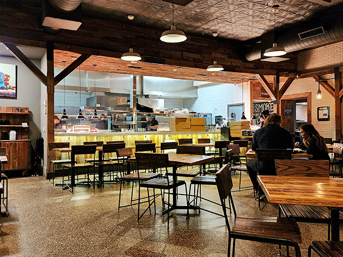 Inside, rustic meets refined with exposed brick, wooden beams, and that open kitchen where barbecue magic happens. That "SMOKE" sign isn't lying to you.