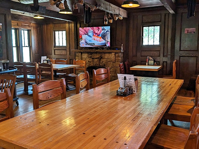 Rustic wooden tables, stone fireplace, and warm lighting create the perfect backdrop for food that demands your full attention and possibly an elastic waistband.