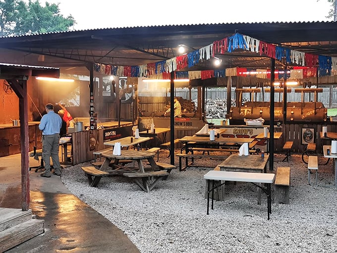 Red, white, and blue streamers flutter above rustic picnic tables where strangers become friends united by the universal language of exceptional barbecue.