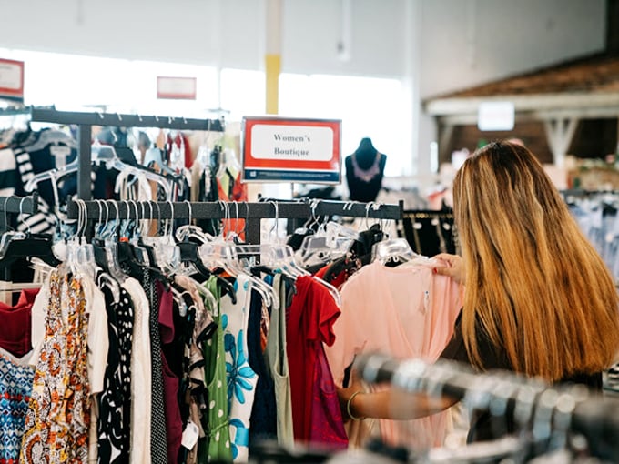 Treasure hunting in action! A shopper sifts through colorful garments in the meticulously organized Women's Boutique section, where yesterday's fashion finds new purpose.