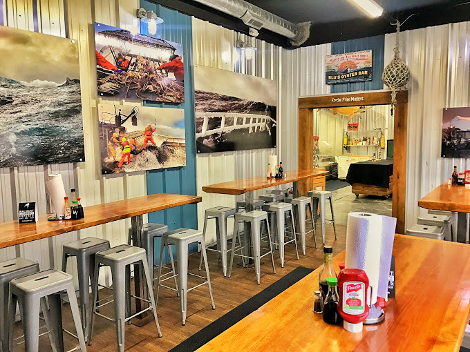 Industrial-chic meets maritime charm in this thoughtfully designed space. Fishing photographs transport diners to distant shores while metal stools invite seafood enthusiasts to pull up and dive in.