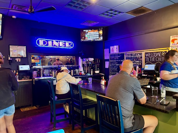 The neon "DINER" sign bathes the counter in a cool blue glow, creating an atmosphere that's both nostalgic and surprisingly hip.