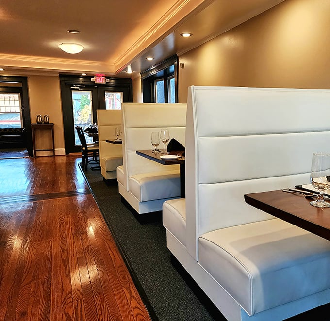 Modern meets cozy in these sleek white booths, where private conversations and intimate dining experiences unfold against warm wooden floors and soft lighting.