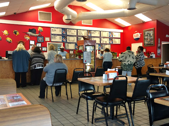 The culinary command center where seafood dreams come true. Red walls, colorful fish decorations, and a menu board that promises delicious decisions ahead.