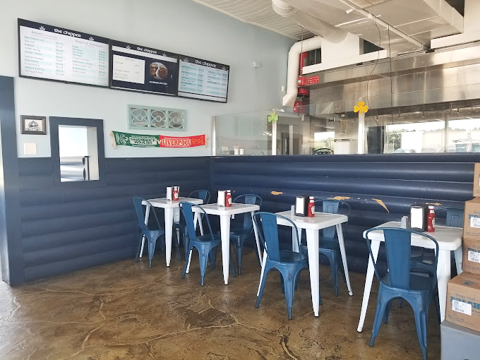 Modern meets maritime in The Chipper's dining area, where blue metal chairs and white tables create a casual vibe perfect for savoring crispy delights.