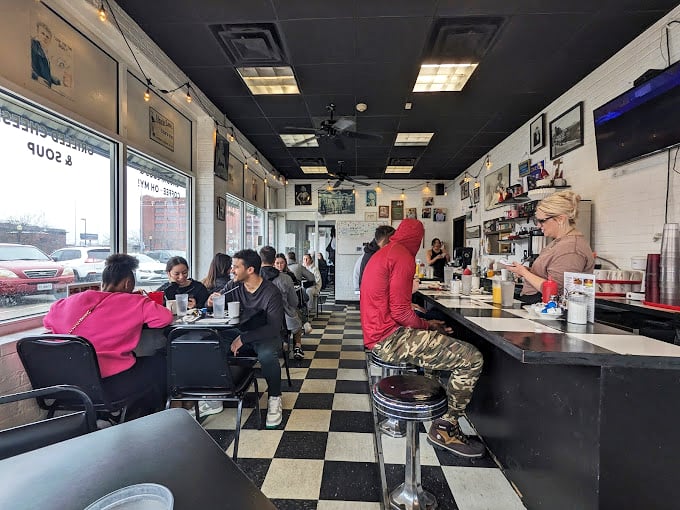 Inside, the checkered floor and counter seating create that quintessential American diner experience where strangers become neighbors over coffee and conversation.