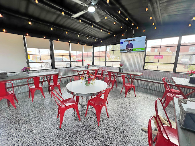 Industrial-chic meets diner comfort in Sid's newer seating area, where those cherry-red chairs pop against concrete floors like exclamation points of hospitality.