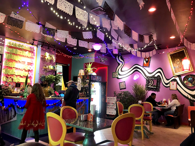 Step inside and you're transported to a kaleidoscope wonderland. The papel picado ceiling and electric purple walls create a joyful atmosphere that's pure sensory overload.