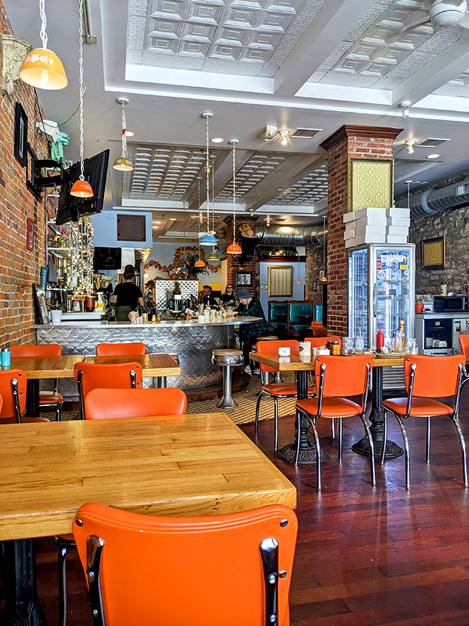 Orange chairs pop against exposed brick walls like exclamation points in a love letter to classic Americana dining.