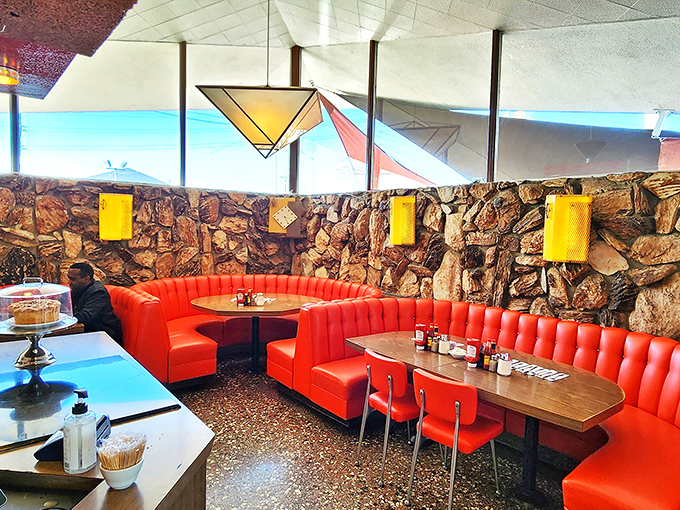 Those flame-red booths aren't just seating &ndash; they're time machines to the golden age of diners, complete with stone walls and geometric ceiling details.