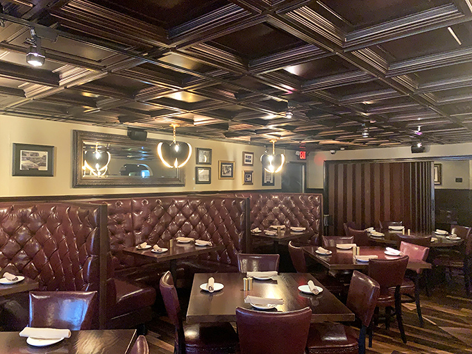 Classic steakhouse elegance: burgundy leather booths, ornate tin ceiling, and lighting dim enough for romance but bright enough to appreciate your prime cut.