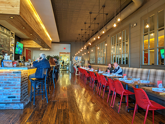 Warm wood floors reflect pendant lighting while red chairs pop against neutral tones. This isn't just a restaurant&mdash;it's Little Rock's living room with better food.