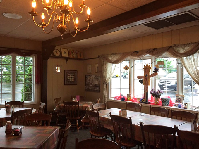Wooden chairs that have supported generations of satisfied diners gather around tables beneath a warm chandelier, creating the dining room equivalent of a bear hug.