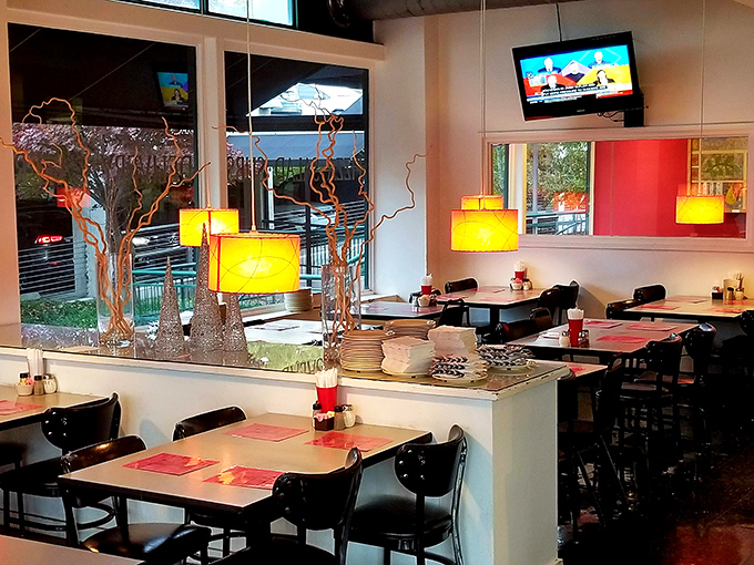 Warm yellow pendant lights cast a golden glow over simple tables with red placemats. This isn't a pizza palace—it's a pizza sanctuary where the food takes center stage.