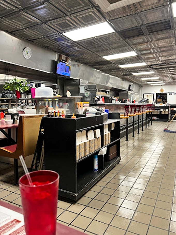 Classic diner counter seating where strangers become friends over coffee. The metallic ceiling tiles above have witnessed decades of Greensboro's morning conversations.