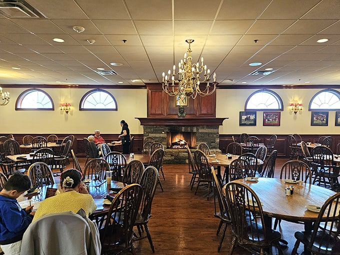 Elegant chandeliers cast a warm glow over Windsor-back chairs and polished wood floors, creating an atmosphere where time slows down for proper dining.