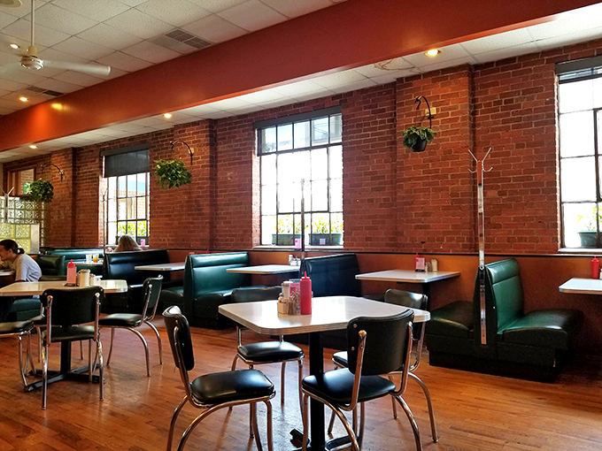 Classic diner aesthetics meet cozy comfort with exposed brick walls, hanging plants, and those unmistakable vinyl booths that have cradled countless happy diners.