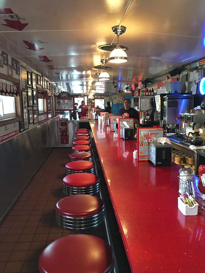 The diner's gleaming red counter stretches into infinity, each stool a front-row seat to culinary theater that's been running continuously since 1922.