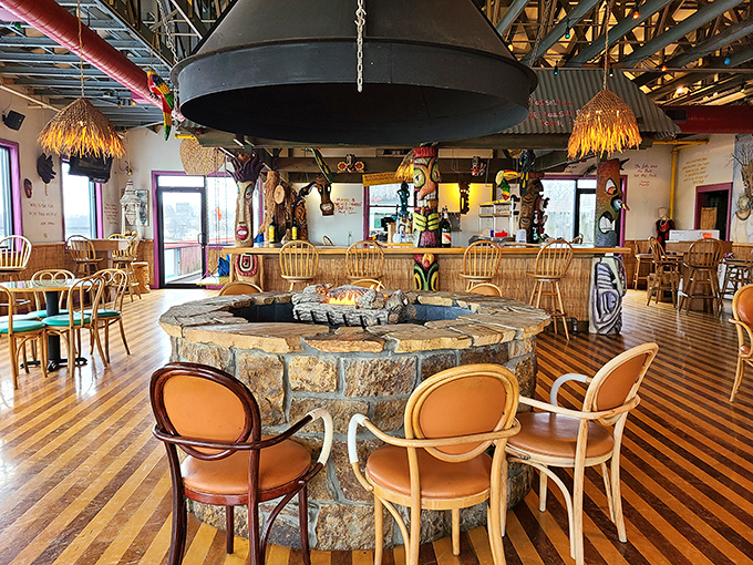 A stone fire pit anchors the dining room, surrounded by wooden chairs and thatched decor that whispers, "Yes, you're still in Ohio, but let's pretend we're not."