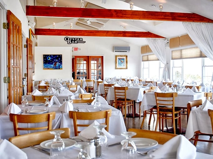 White tablecloths meet warm wooden beams in this dining room where comfort and elegance dance a perfect tango.