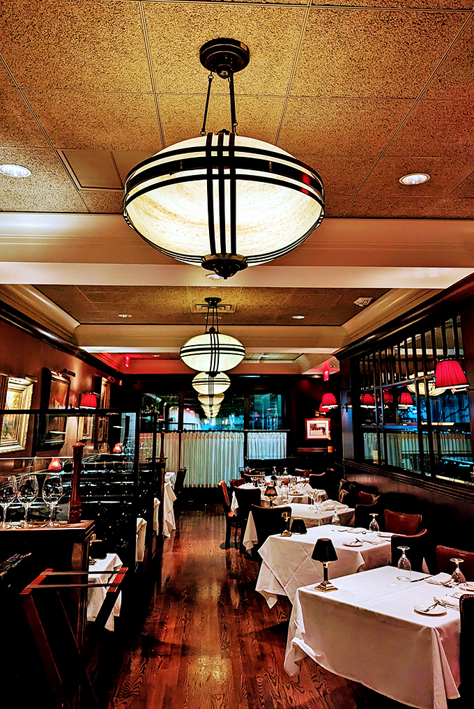 Art Deco fixtures cast a warm glow over white tablecloths, creating that rare atmosphere where conversations flow as smoothly as the wine.