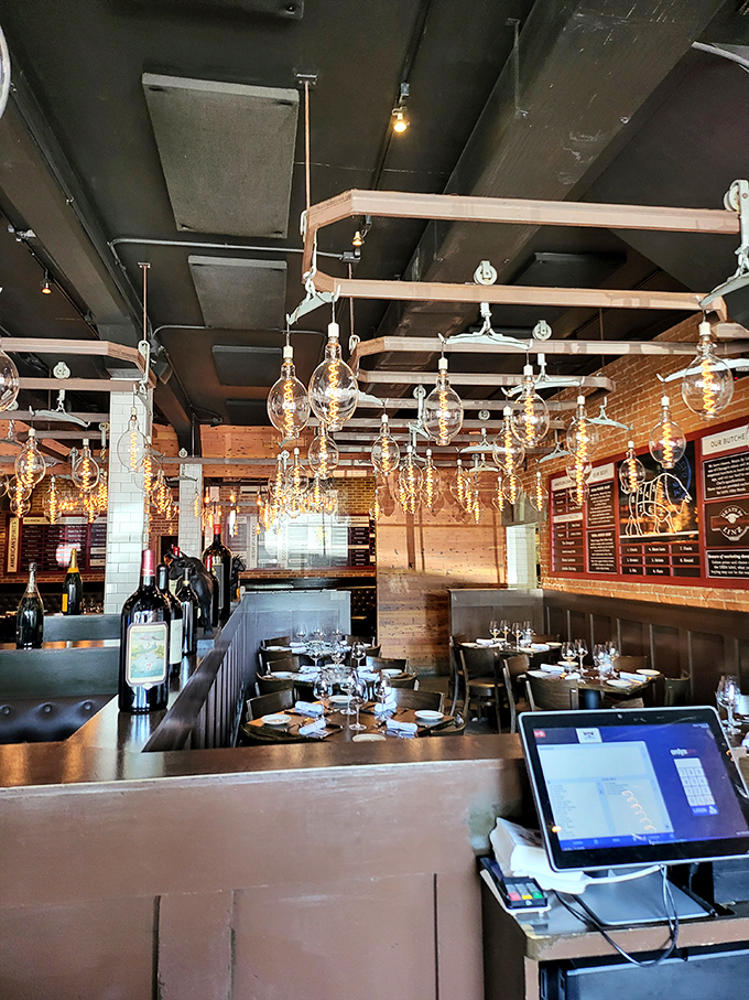 Warm Edison bulbs dangle like golden jewelry above the dining room, creating an atmosphere that says "special occasion" while still whispering "come as you are."