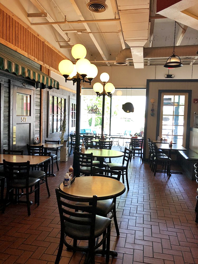 Step inside to a warm, inviting space where vintage-style street lamps cast a golden glow over brick floors—comfort and nostalgia served before your meal even arrives.