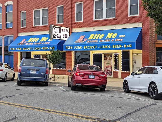 Bite Me BBQ: "Blue awnings, brick building, and a name that tells you exactly where they stand. No pretension, just meat perfection."