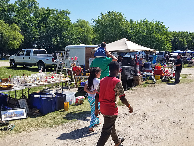 Blue tarps and eager shoppers create the perfect weekend ritual. Every table holds someone's future "you'll never believe what I found" story.