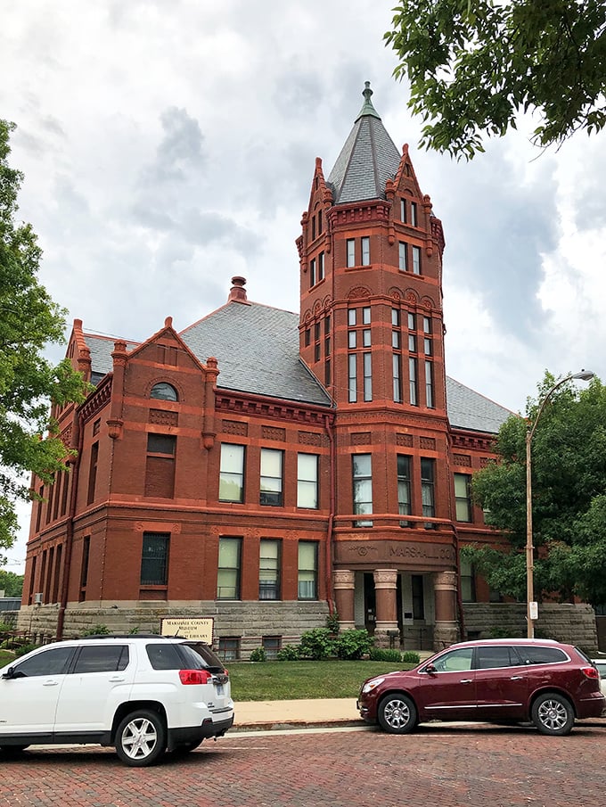 The Marshall County Courthouse stands like a Victorian sentinel, its red brick tower watching over generations of small-town life with dignified grace.