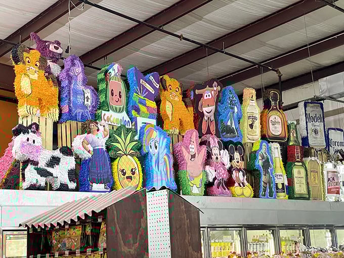 A rainbow explosion of pi&ntilde;atas watches over shoppers like whimsical guardians, proving everything's more fun when suspended from the ceiling.