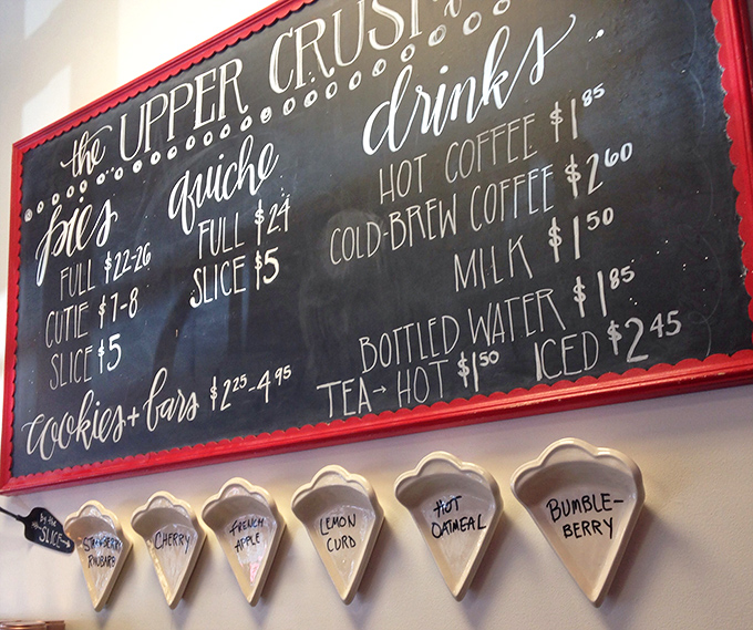 Life's important decisions happen at this menu board. The ceramic pie slice labels below are the kind of detail that separates good bakeries from great ones.
