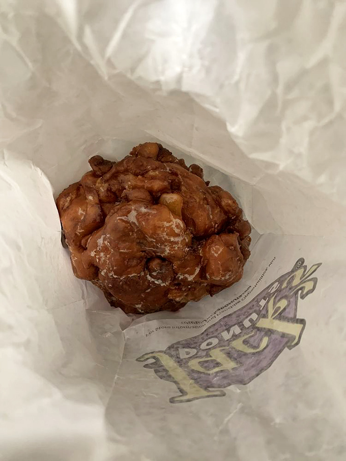 This apple fritter isn't just a donut—it's a monument to excess wrapped in wax paper, with glorious chunks of apple peeking through the glaze.