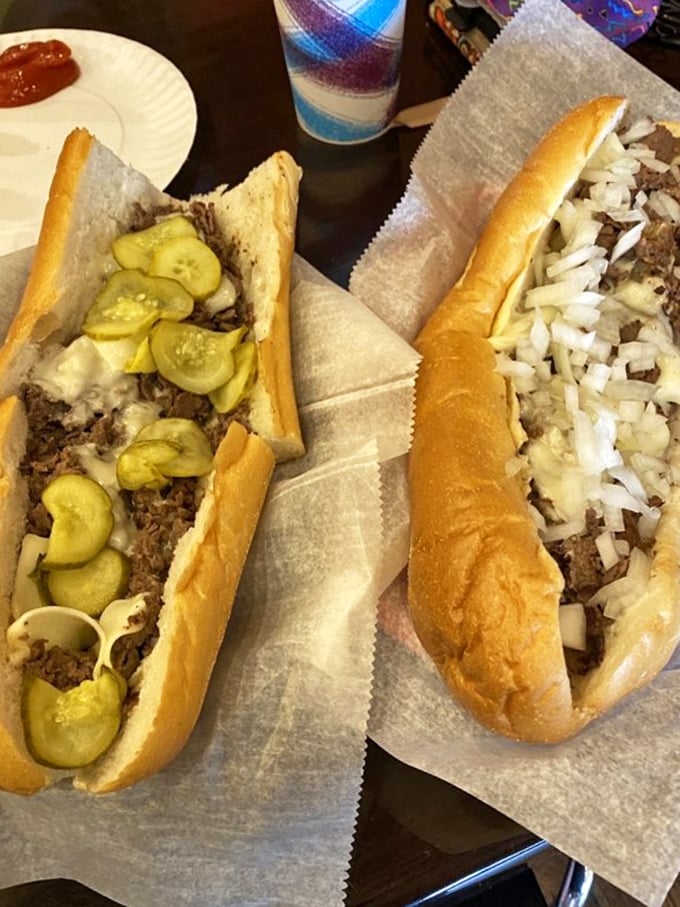 A tale of two cheesesteaks: one adorned with tangy pickles, the other showcasing classic onions. The eternal question - which path to sandwich nirvana?